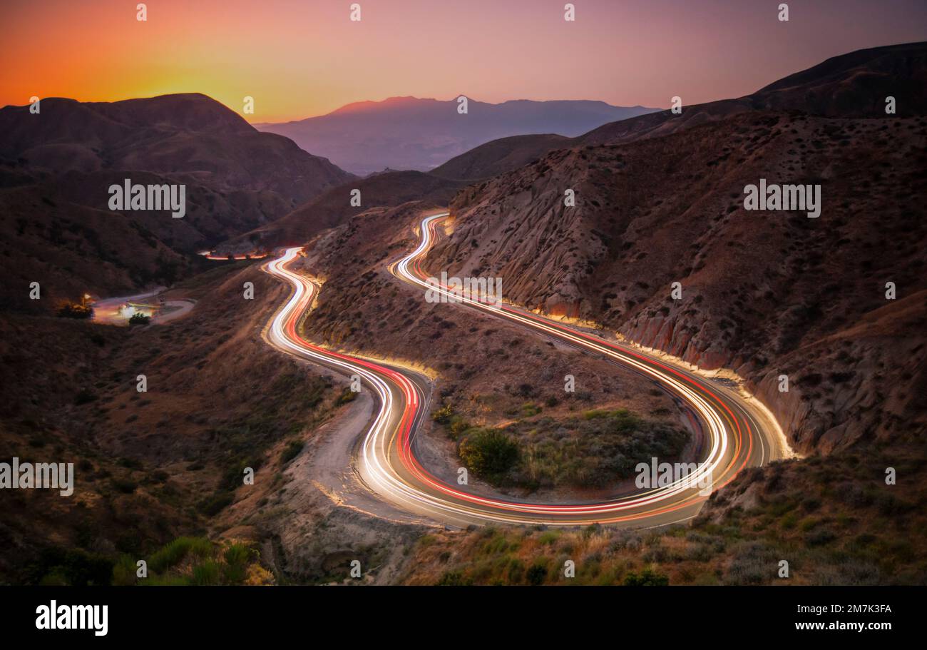 A landscape of roads on hills with long exposure car trails during a ...