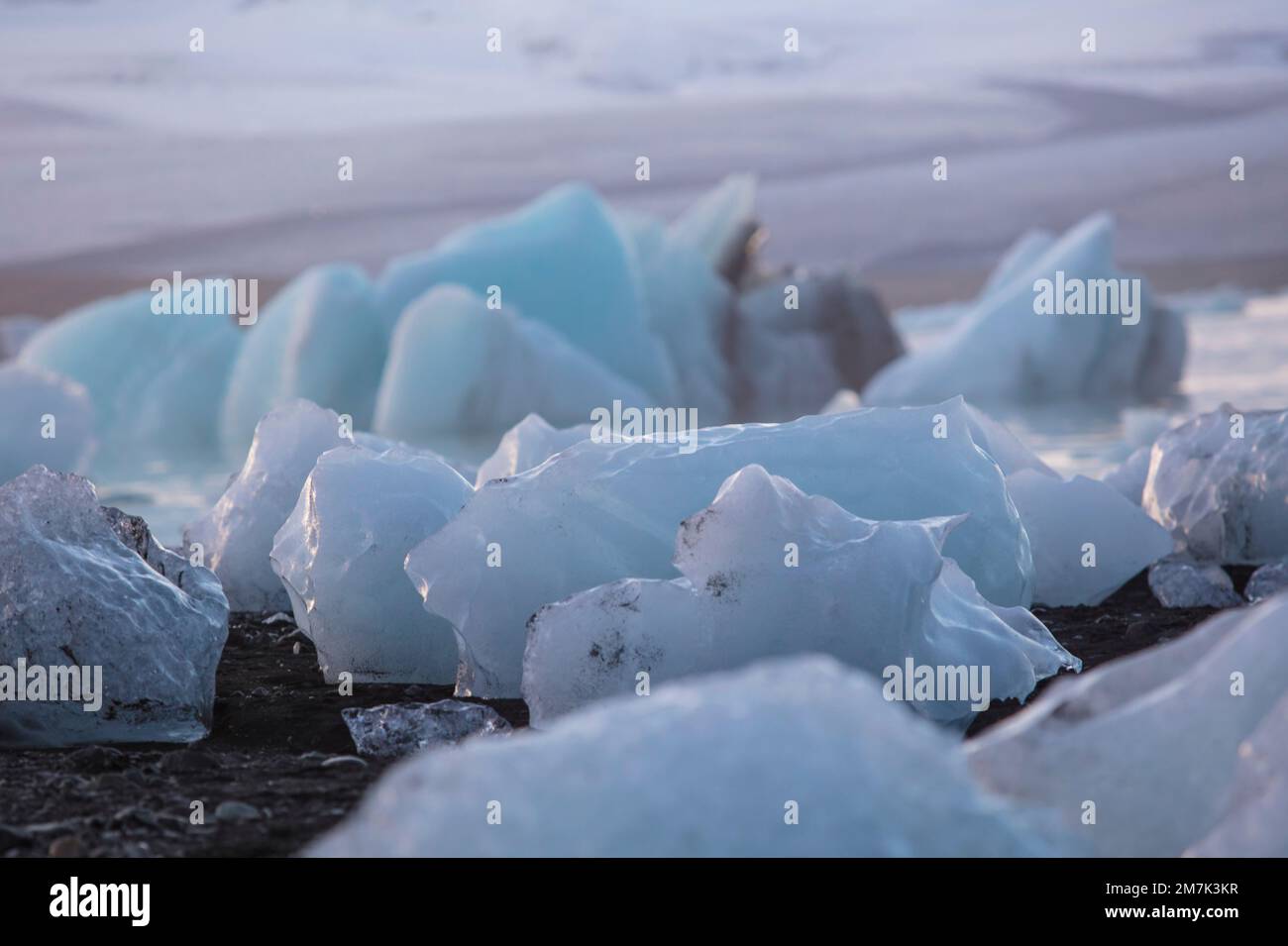 A closeup of ice on the shore of Jokulsarlon in Iceland with a blurry ...