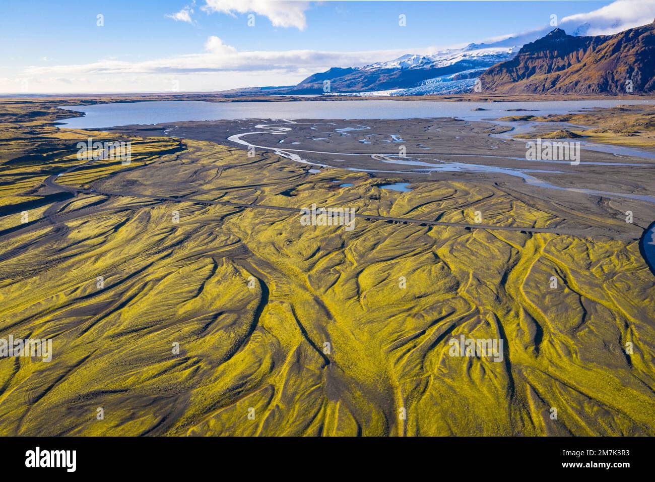 A landscape of the Markarfljot river in a field covered in greenery in ...