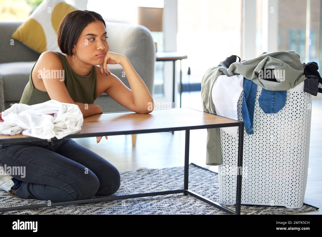 Bored, sad and woman cleaning laundry, housework stress and tired of ...