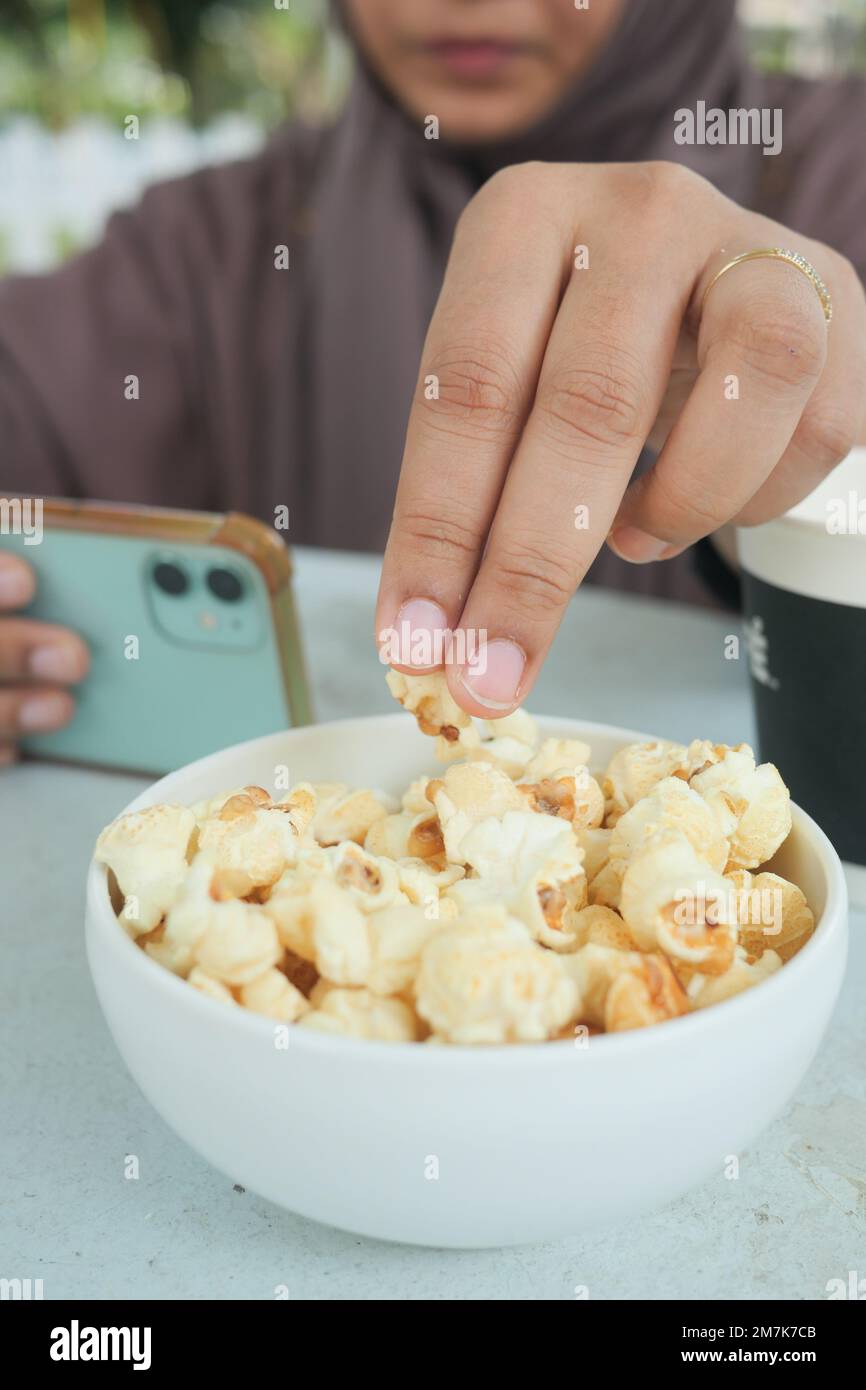 young women eating popcorn and using smart phone Stock Photo - Alamy
