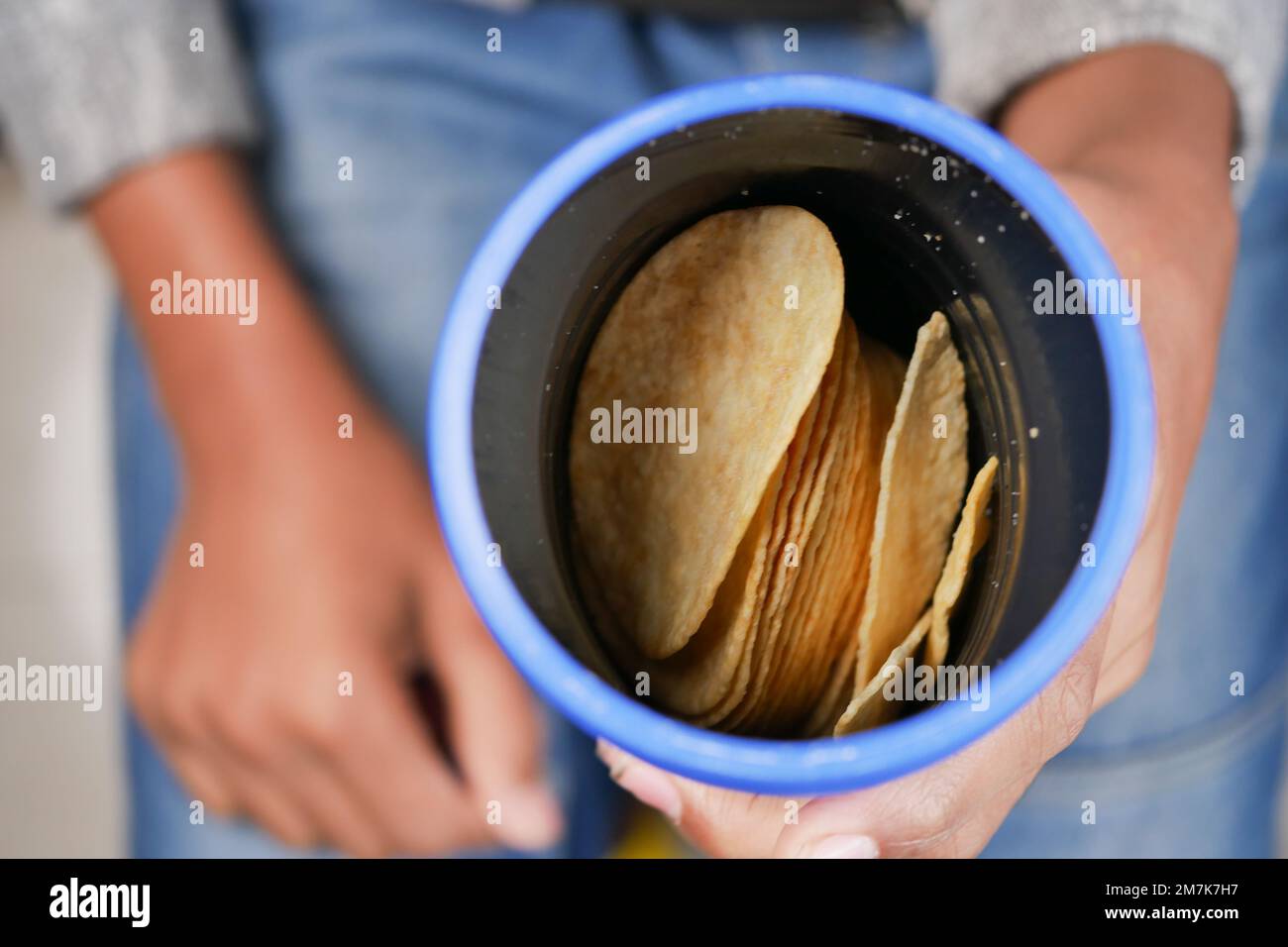 holding a plastic container full of potato chips Stock Photo - Alamy