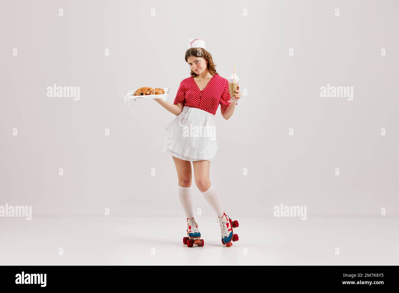 Beautiful young girl in image of retro cater waiter wearing 70s, 80s fashion style uniform ...