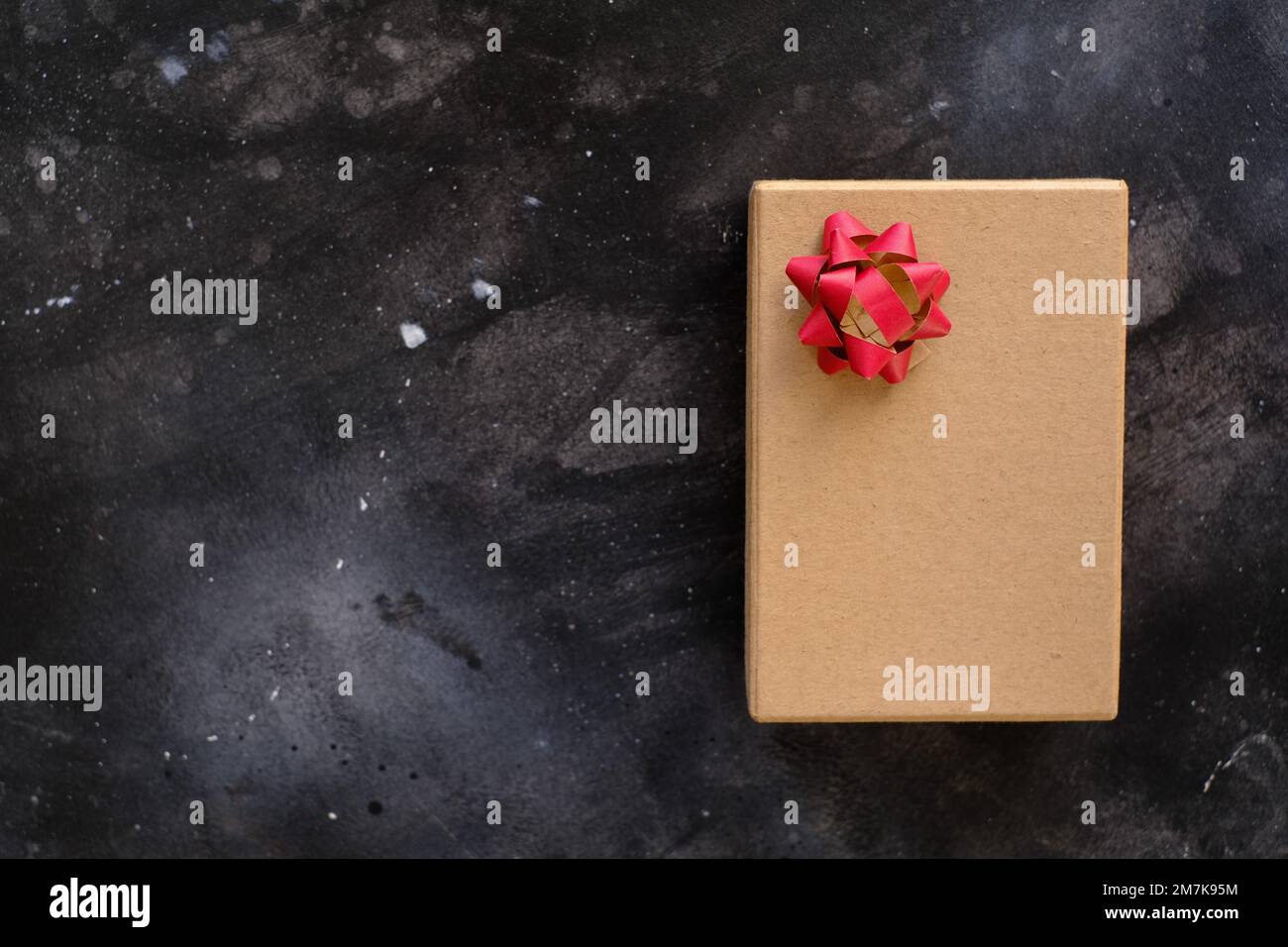 Brown gift box with a red ribbon on dark background Stock Photo - Alamy