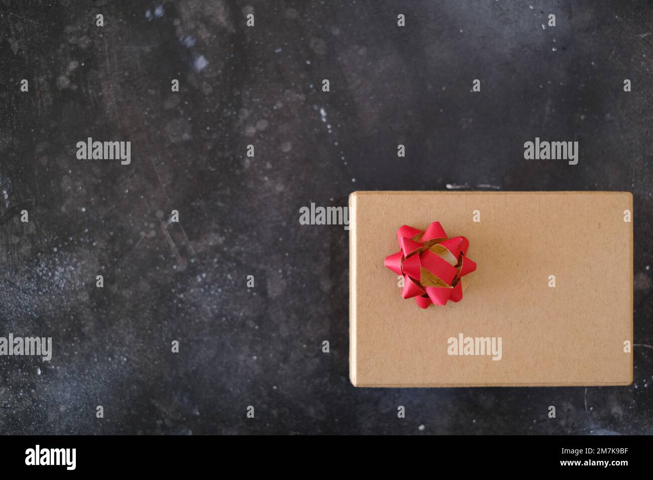 Brown gift box with a red ribbon on dark background Stock Photo - Alamy