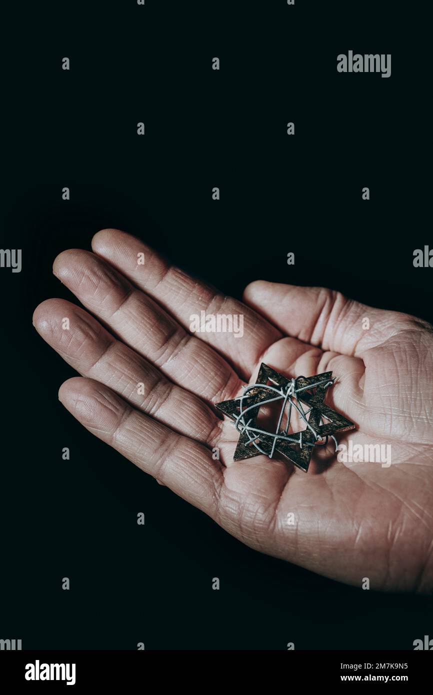 the hand of a man with a star of david tied with some barbed wire ...