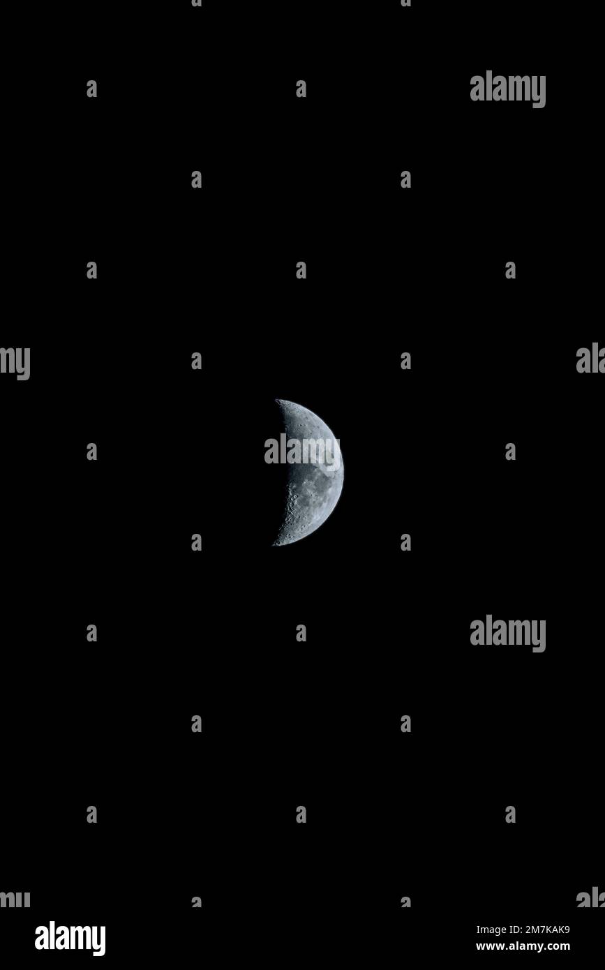 A vertical grayscale of the half-moon shining bright in the night sky ...