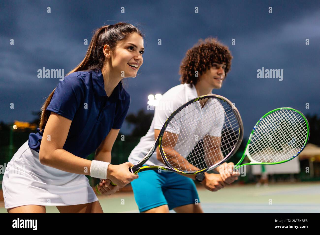 Beautiful young people are playing tennis as a team on tennis court ...