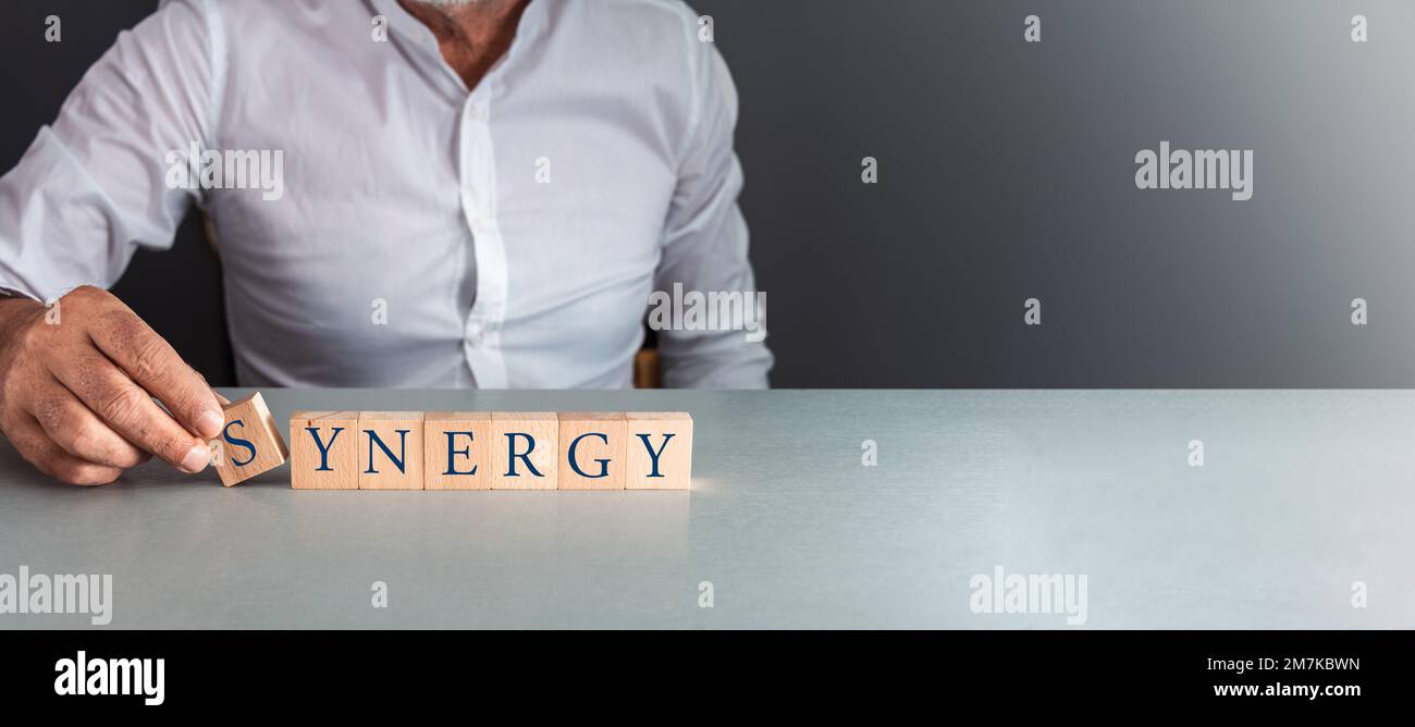 man posing wooden blocks with the word synergy , concept of team work ...