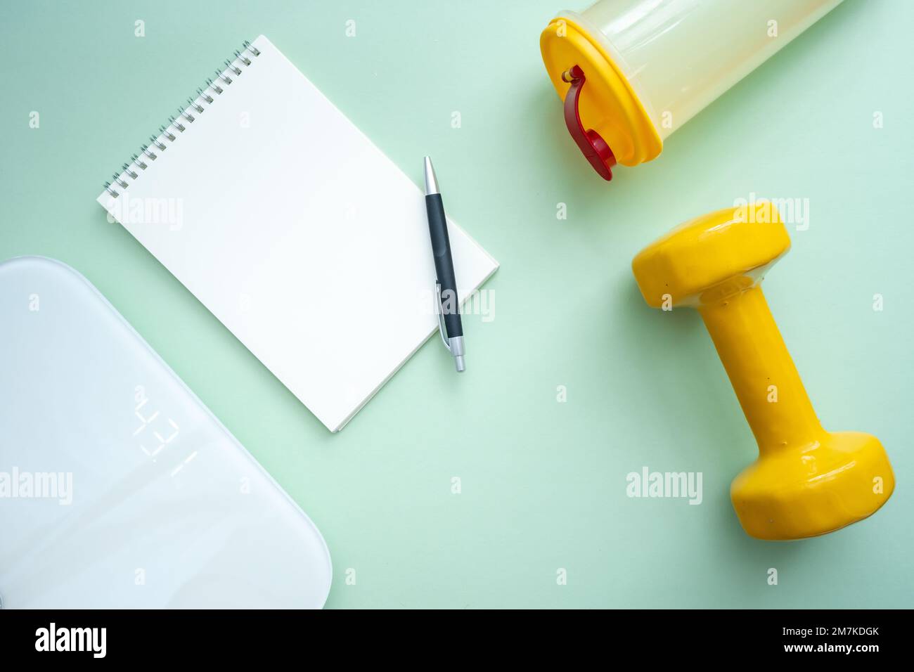 Weighing scale, trendy yellow dumbbells water bottle and notebook on ...