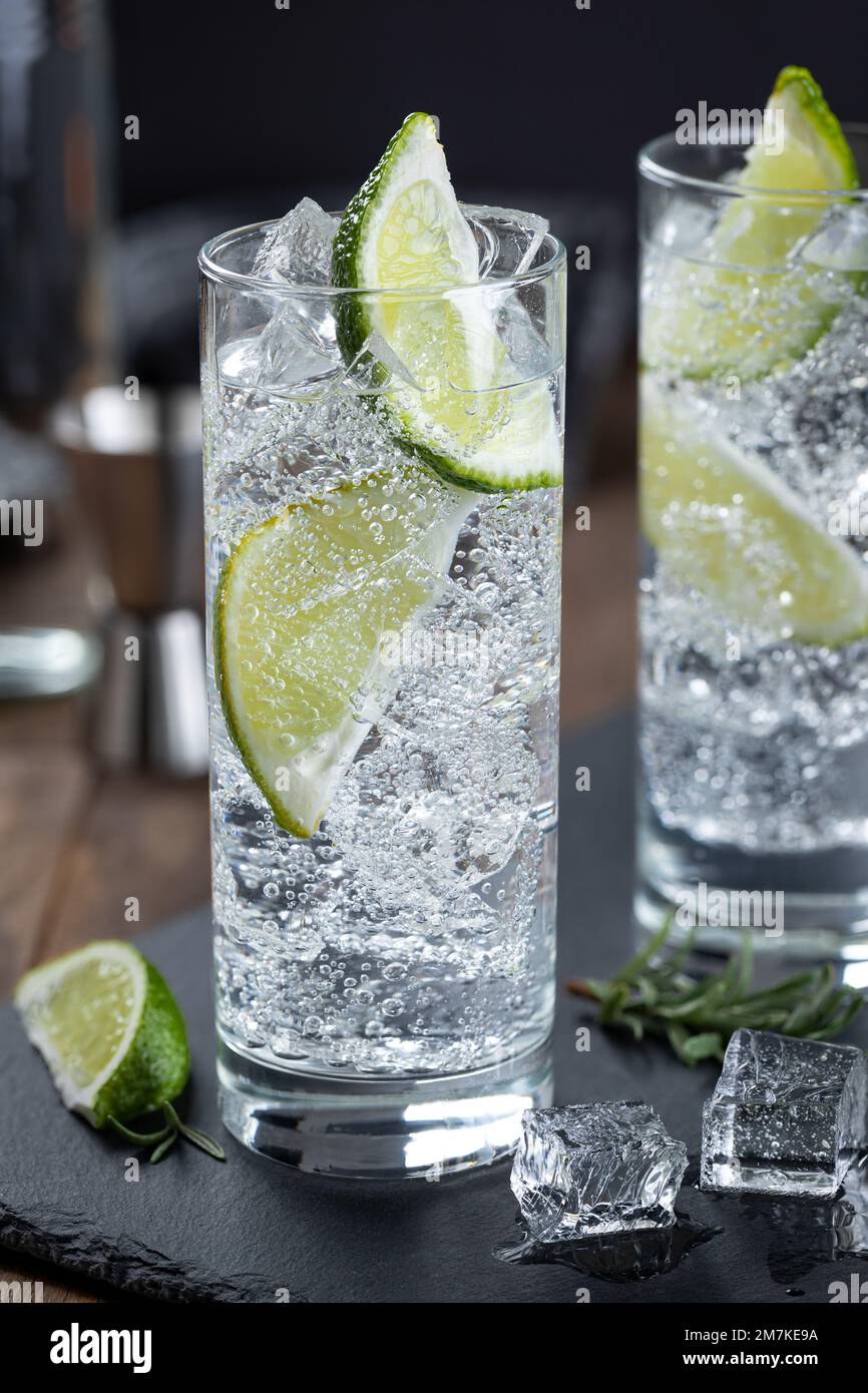 Gin and tonic cocktail with lime slices, and ice in a tall glass on a black slate board Stock ...