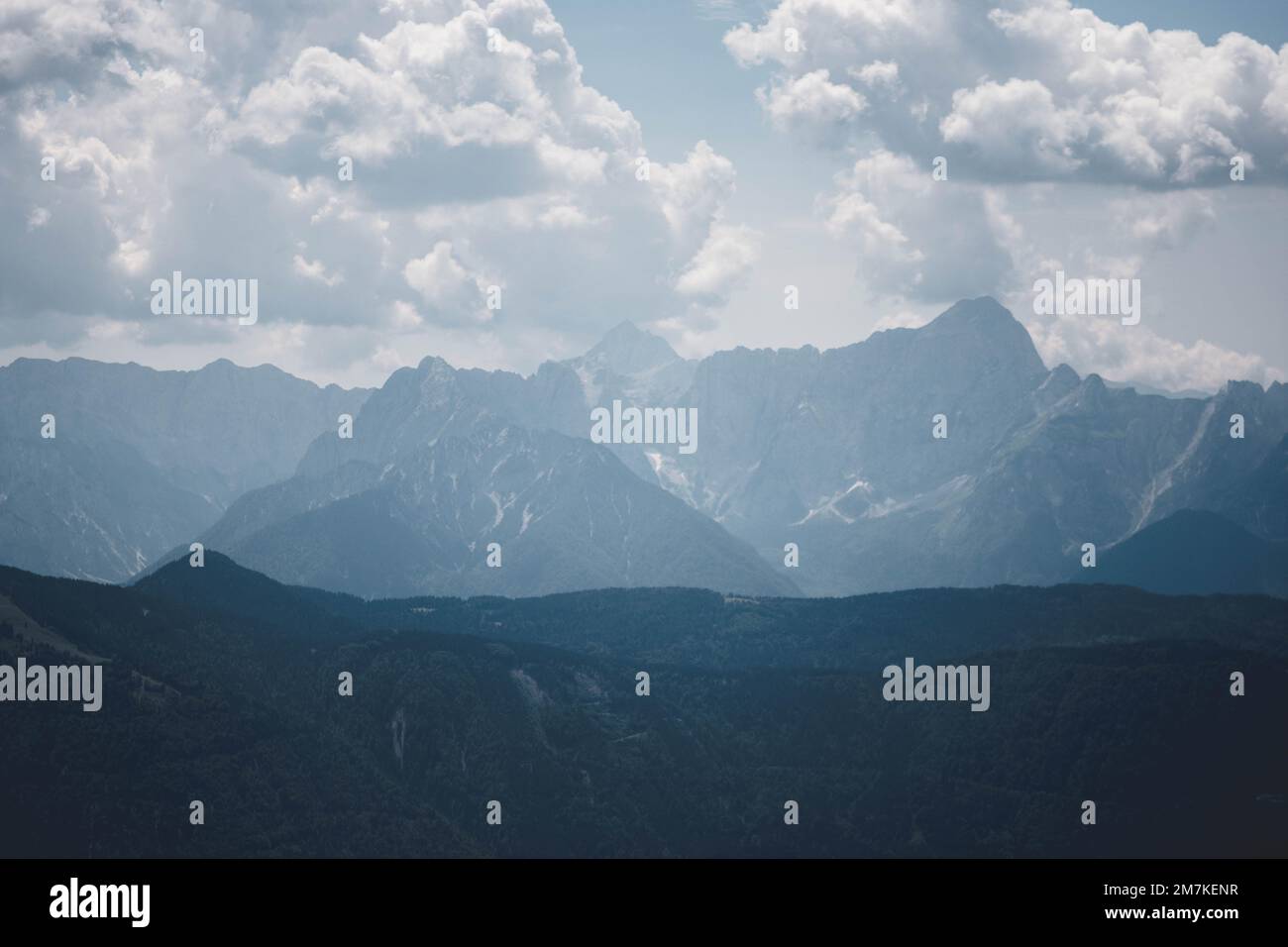 A breathtaking view of huge rocky mountains looming over grassy fields ...