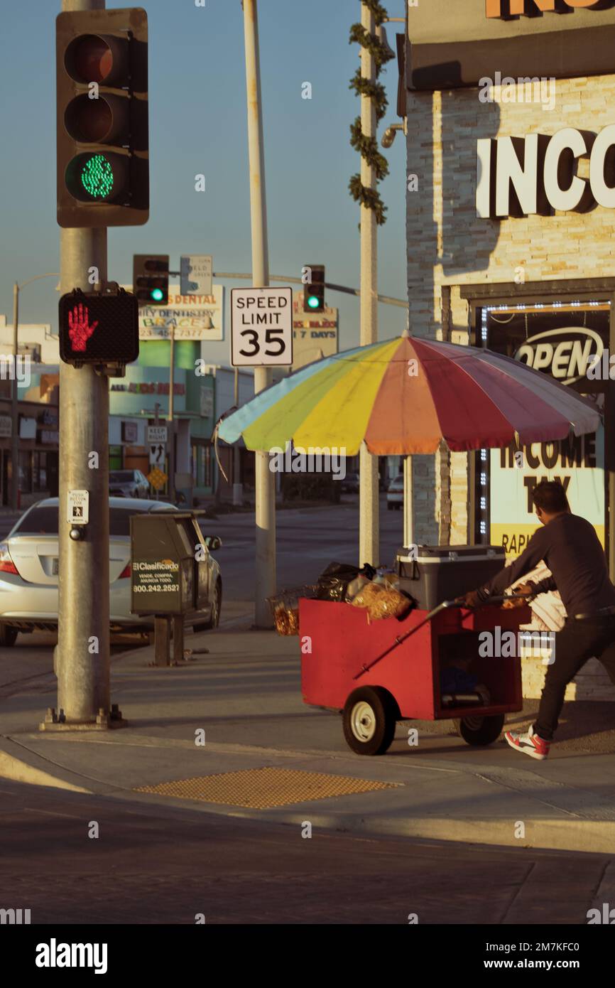 A Raspado Man pushes red cart with rainbow umbrella down Atlantic Ave ...
