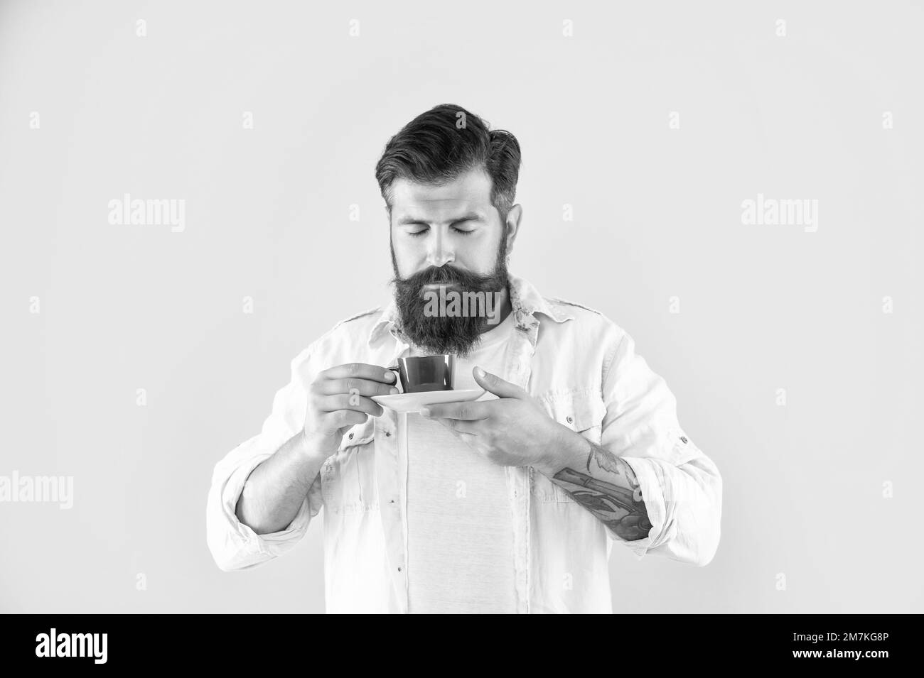 Serious caucasian man with closed eyes smelling tea holding cup and ...