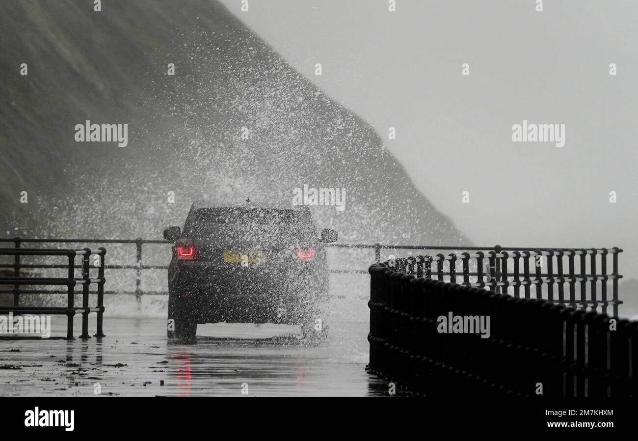 Waves crash over the promenade during rain and strong winds in ...