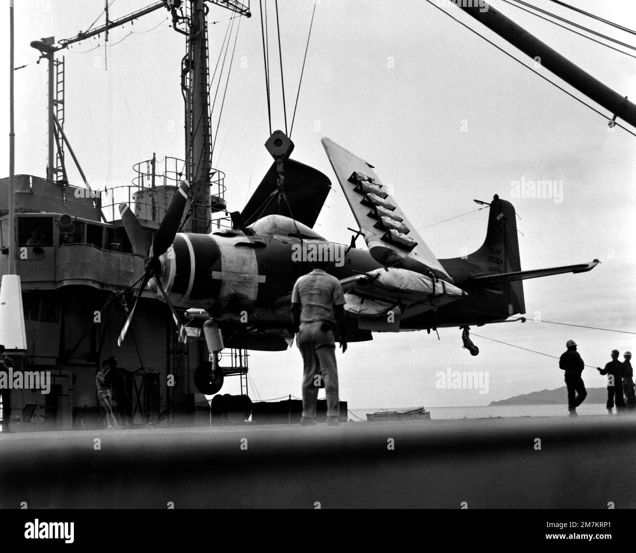 An A-1H Skyraider aircraft is lifted to a barge, the first step in ...