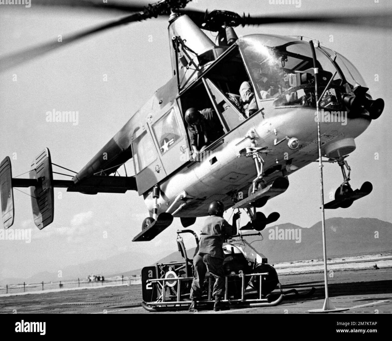 A View of an HH-43B Huskie helicopter as a fireman hooks a fire ...