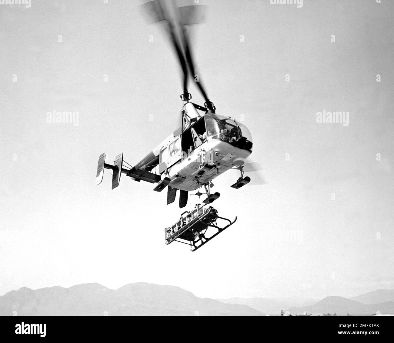 A right underside view of an HH-43B Huskie helicopter lifting a fire ...