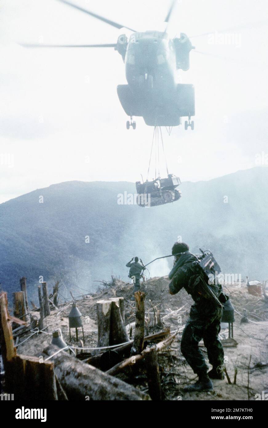A CH-53 Sea Stallion helicopter airlifts a bulldozer into a mountain ...