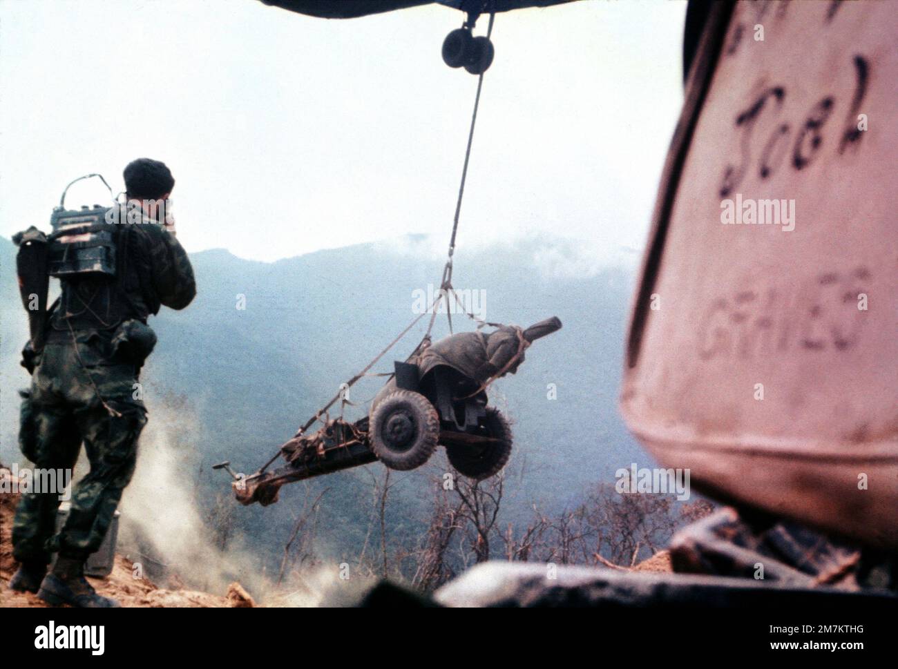 A helicopter lowers an M101 105 mm howitzer into position during the ...