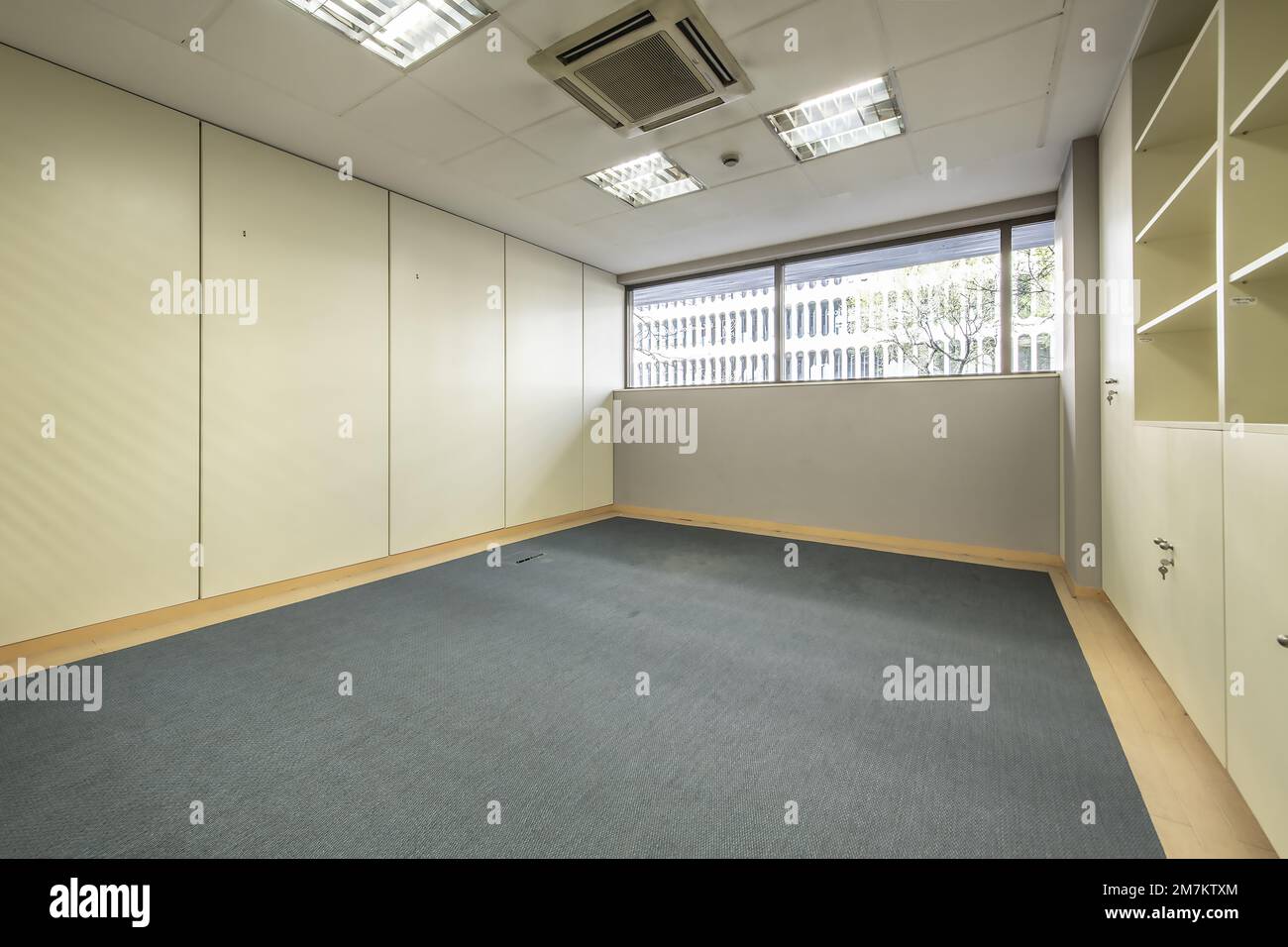 An empty office office with blue carpeted floors and filing cabinets ...