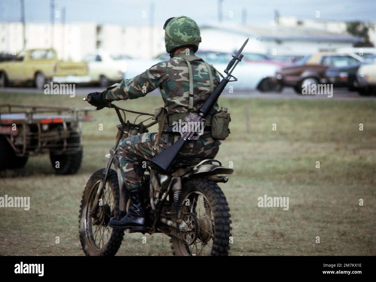 A U.S. Army soldier rides a camouflaged motorcycle. A bayonet is ...