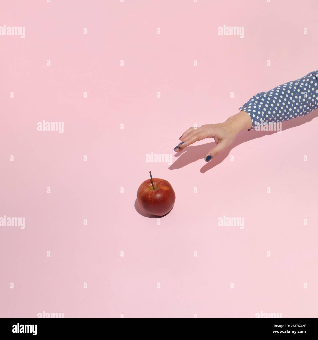 Female hand reaching for fresh apple on pink background. Minimal ...