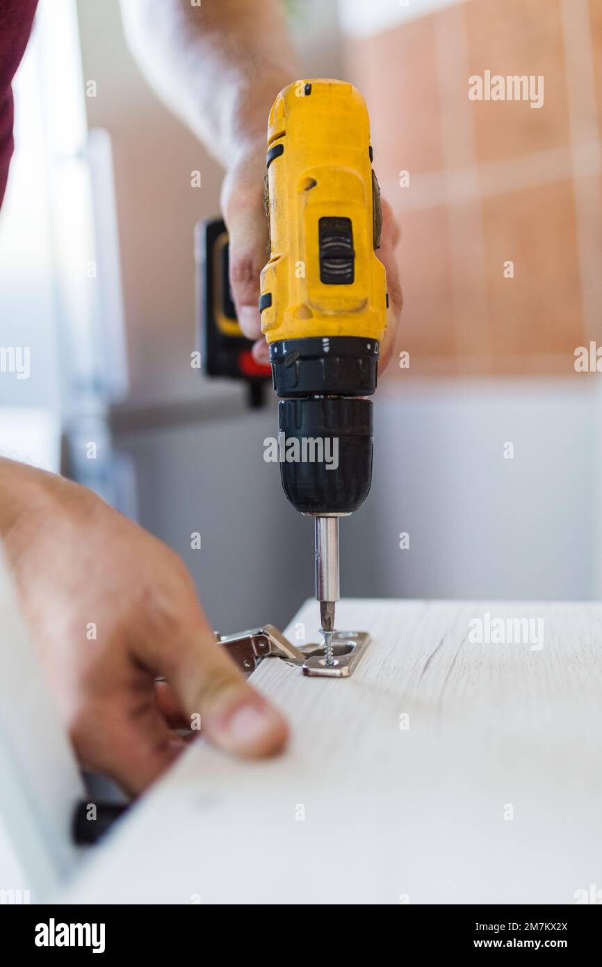 Close up man holding cordless screwdriver machine and screws lie for ...