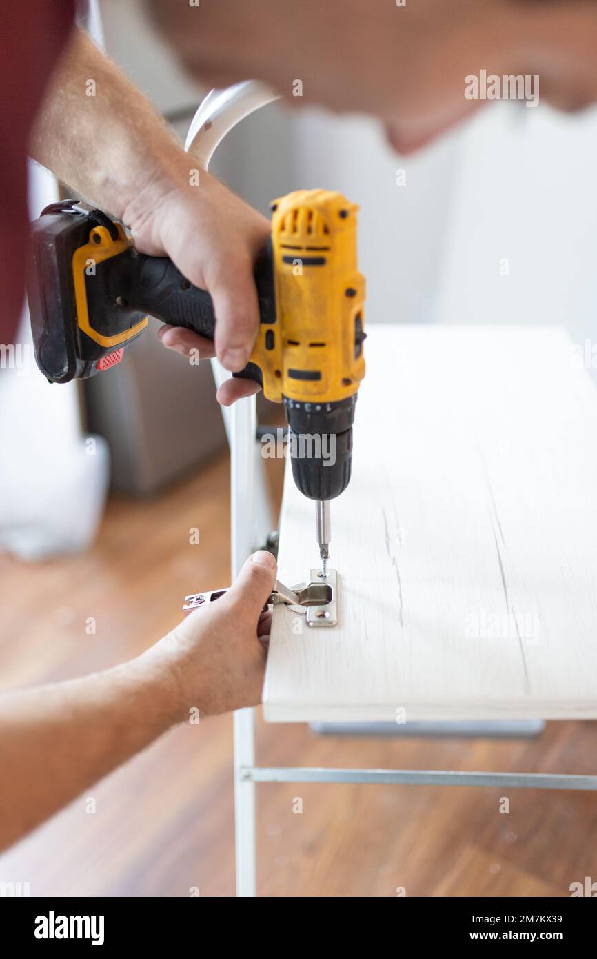 Close Up Of Man Assembling Furniture By Using Cordless Screwdriver