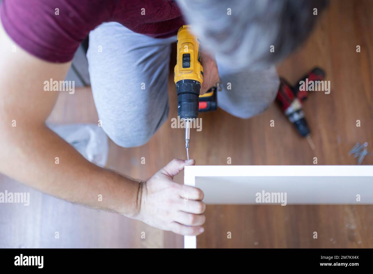 Man installing wooden shelves by using cordless screwdriver Stock Photo ...
