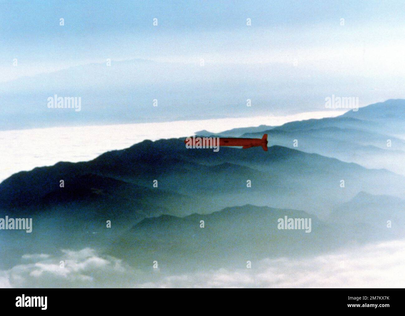 A U.S. Navy Tomahawk cruise missile flies over mountainous terrain ...