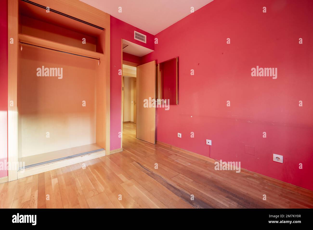 Empty room with deteriorated wooden floor with red walls and cupboard ...