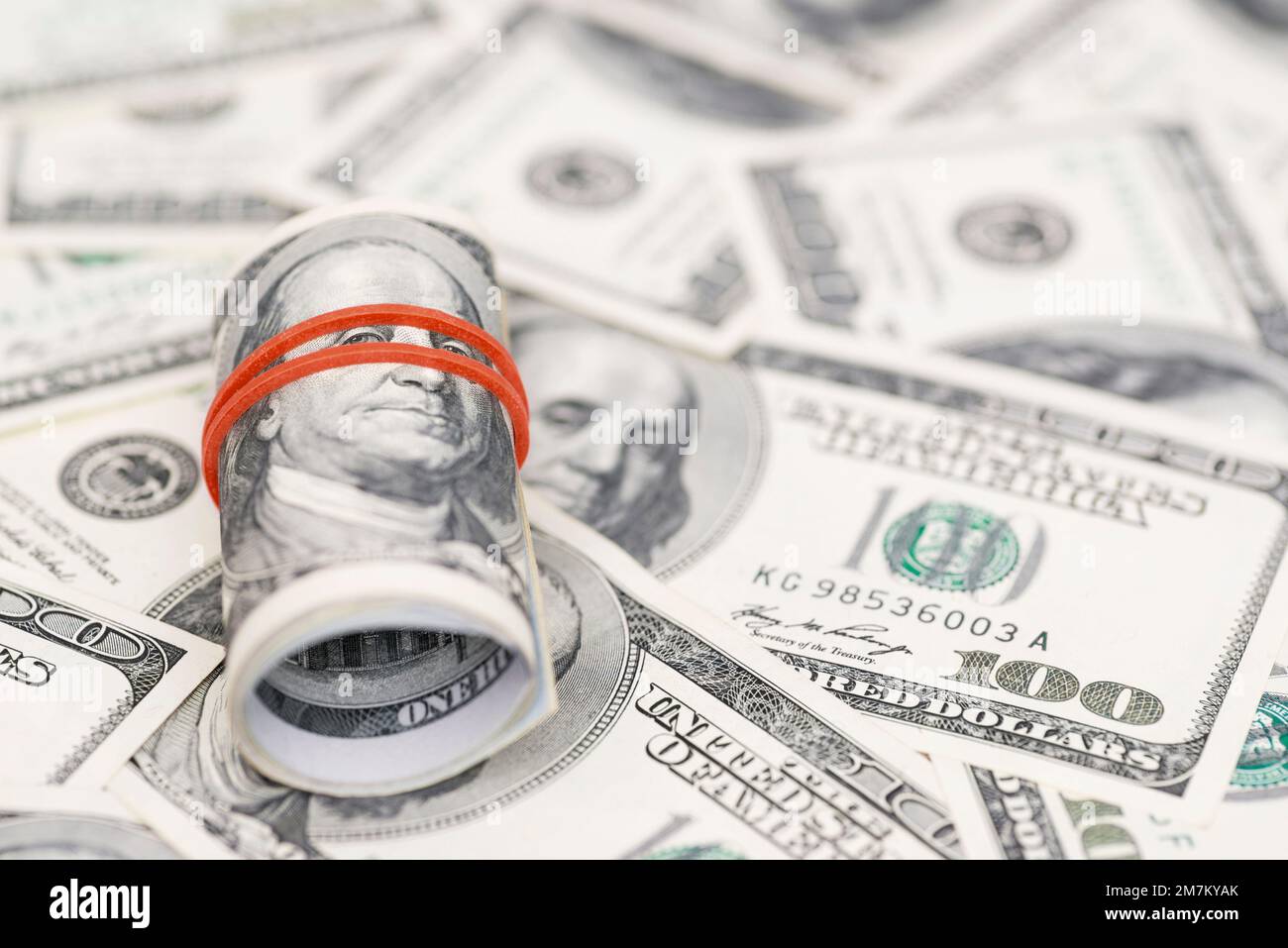 A roll of 100 dollar bills close-up on a pile of American dollars Stock ...