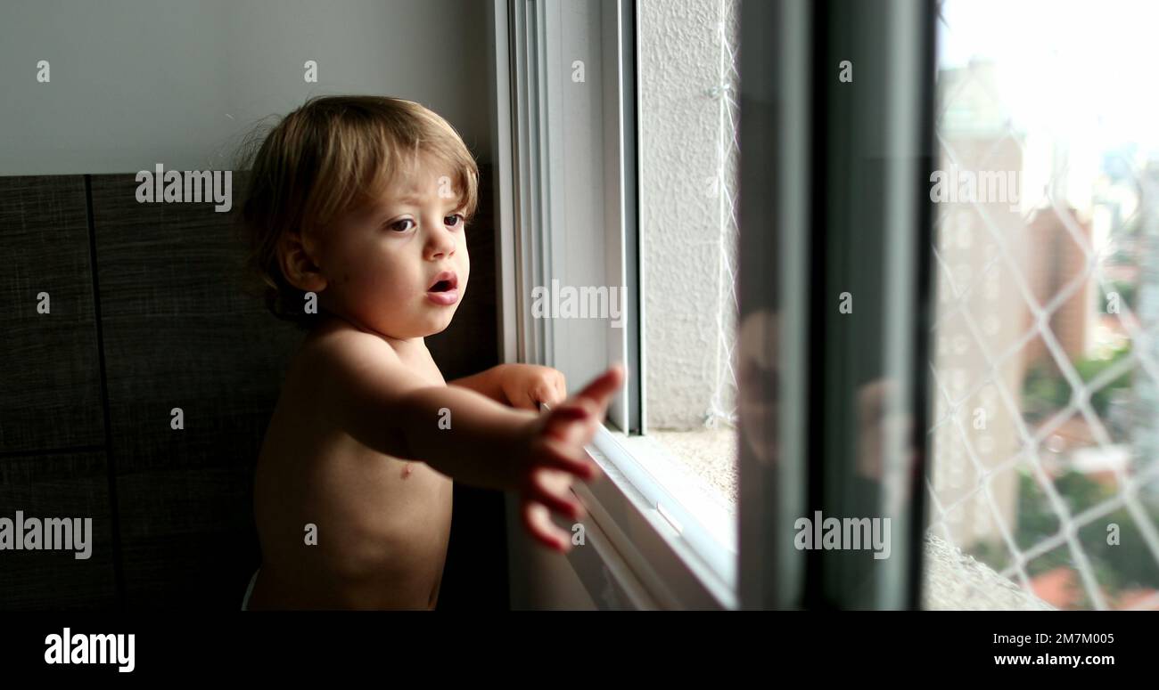 Toddler boy shutting window, child slides apartment window Stock Photo ...
