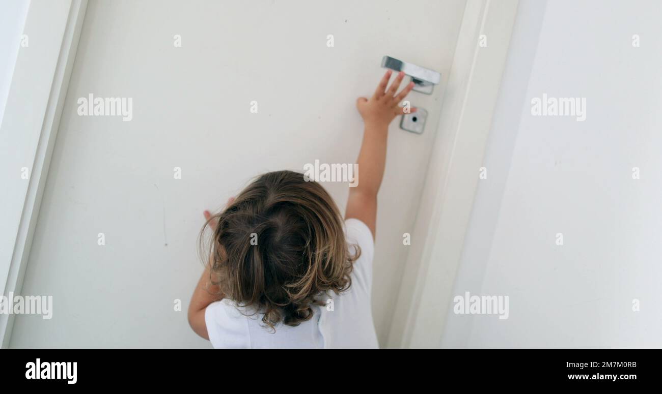 Baby trying to reach door knob. Child on tip toes reaching for door ...