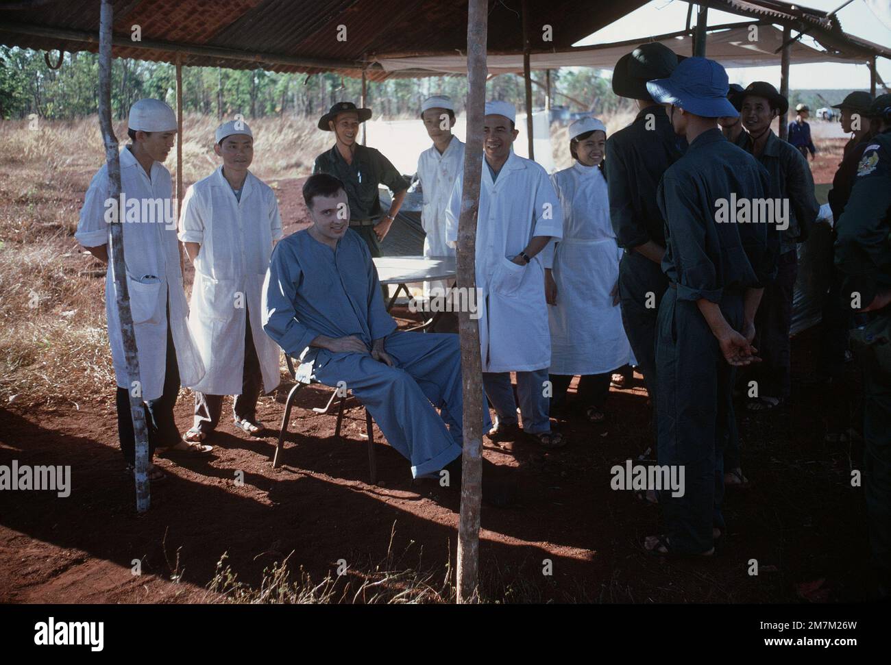 Surrounded by Viet Cong medical personnel, injured American POW, CPT ...