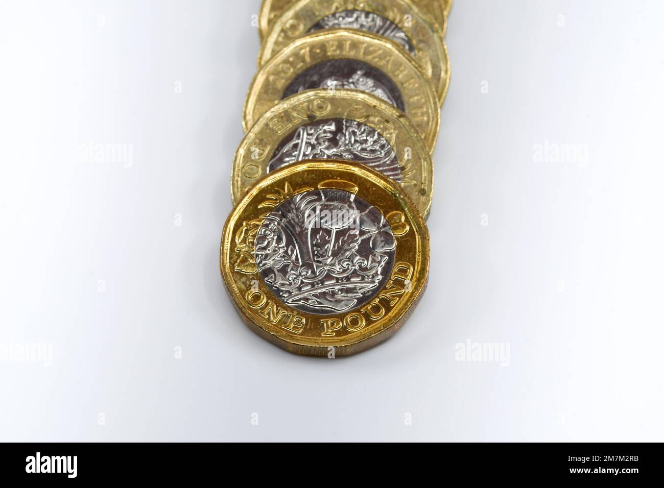 Close up view of a row of British One Pound coins isolated on a plain ...