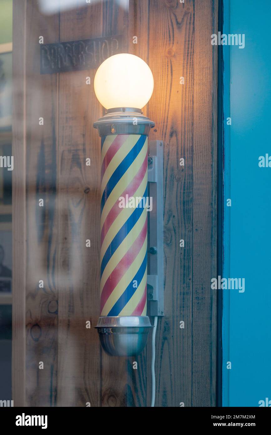 Illuminated Barber's pole inside a small barber shop in London Stock ...