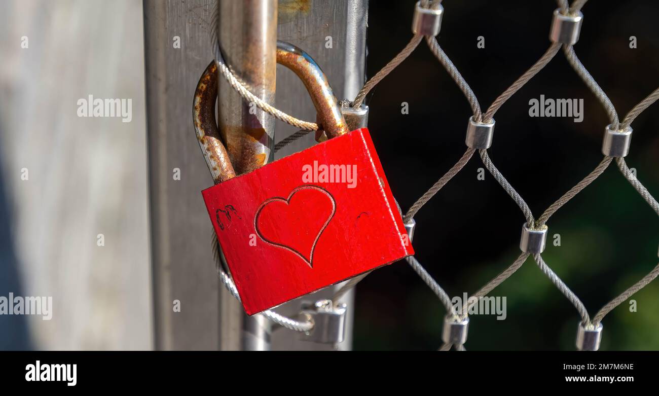 A red padlock with an engraved heart on a fence Stock Photo - Alamy