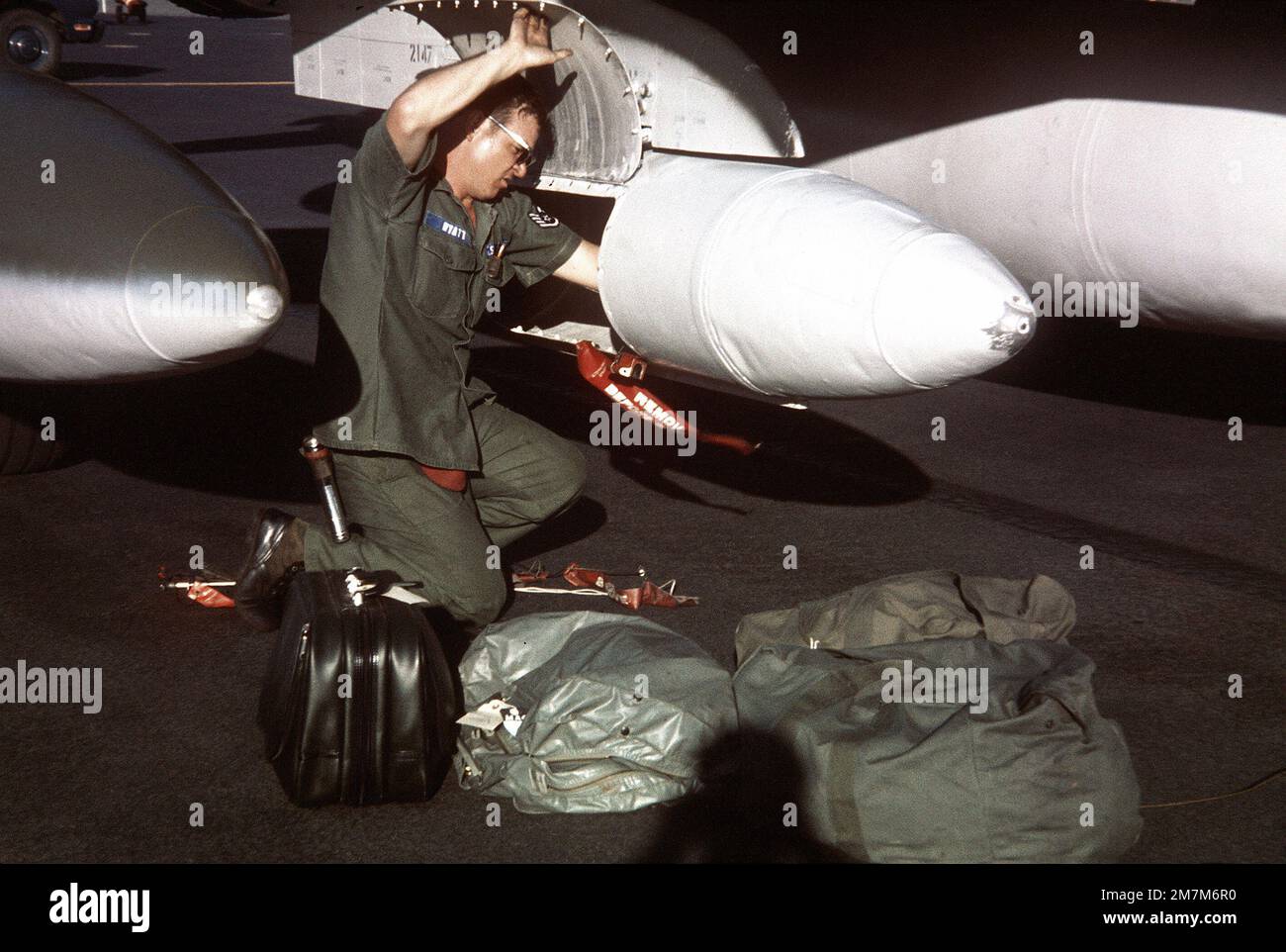 A maintenance crewman unloads fly-away kits from the luggage pod of an ...