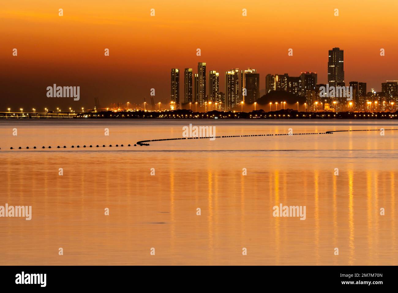 A beautiful view of ocean waves and modern buildings during sunset ...