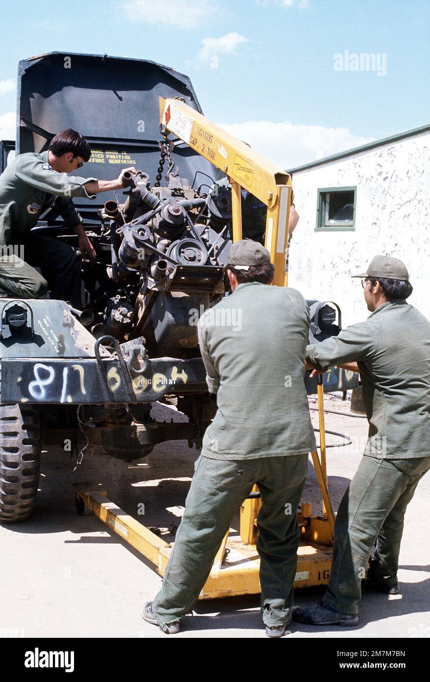 Three Air National Guardsmen remove the engine of a vehicle during ...