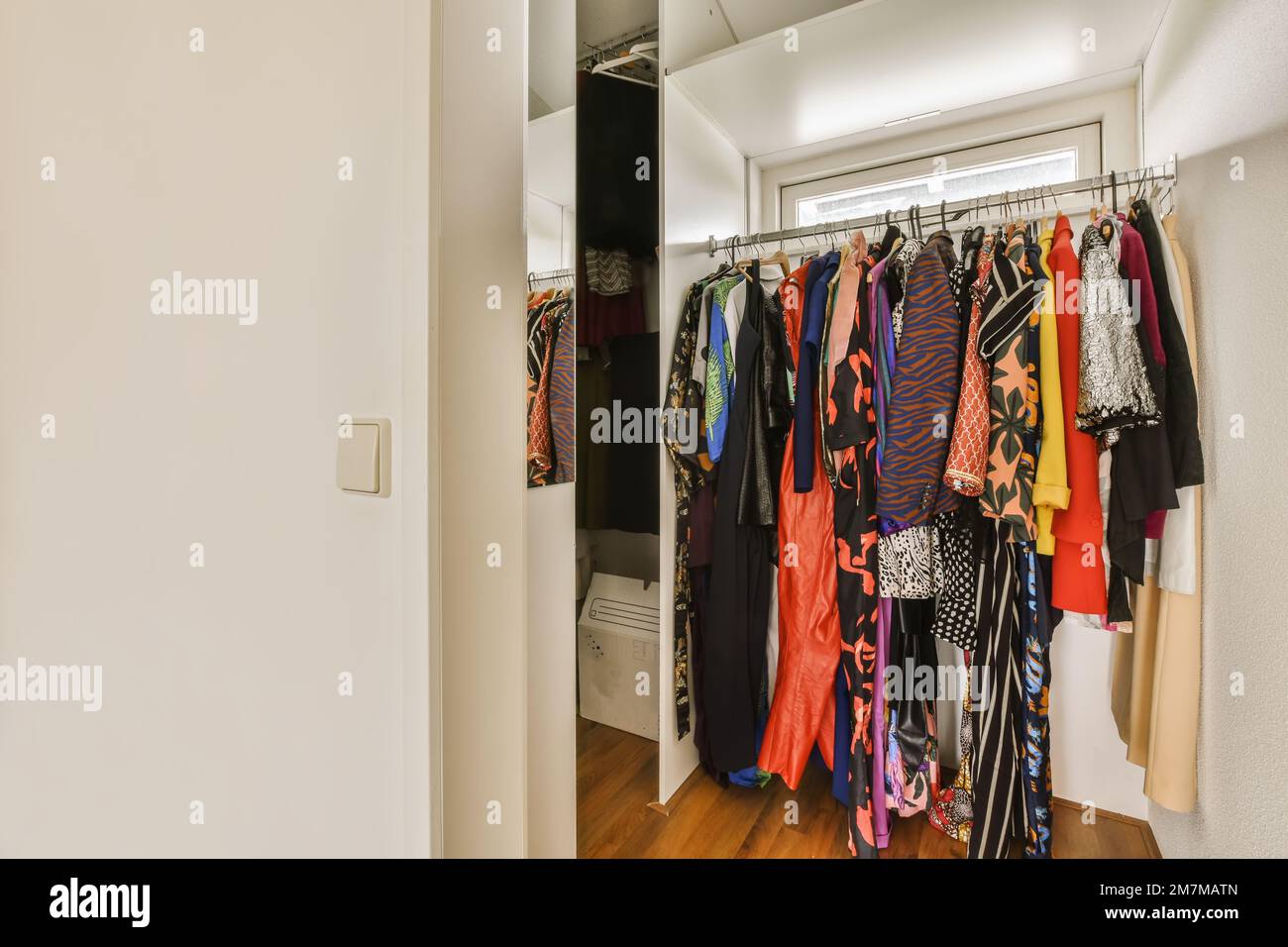 a walk in closet with clothes hanging on the wall and an open door that ...