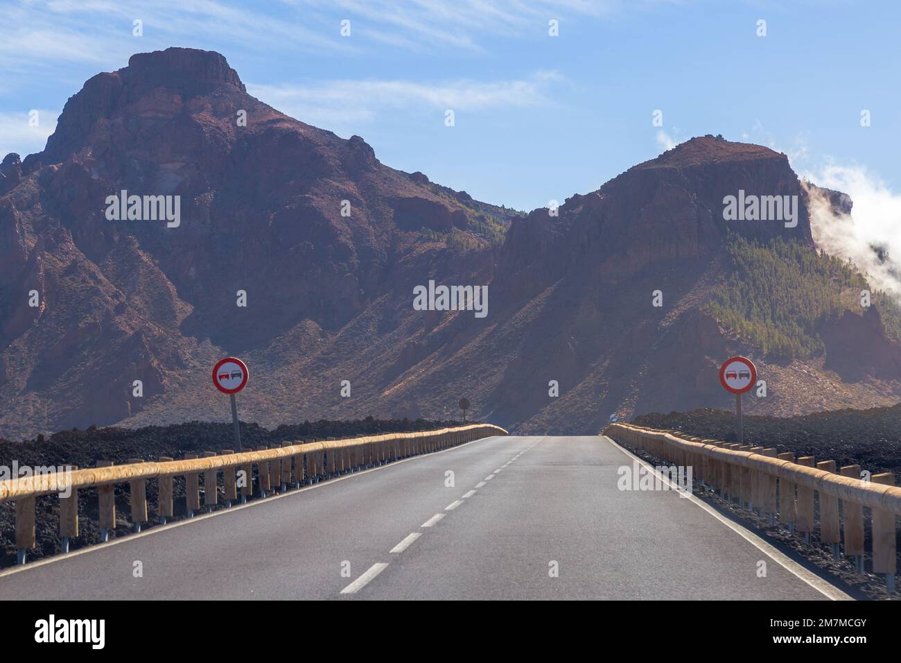 A highway with road signs going straight on towards two massive brown ...