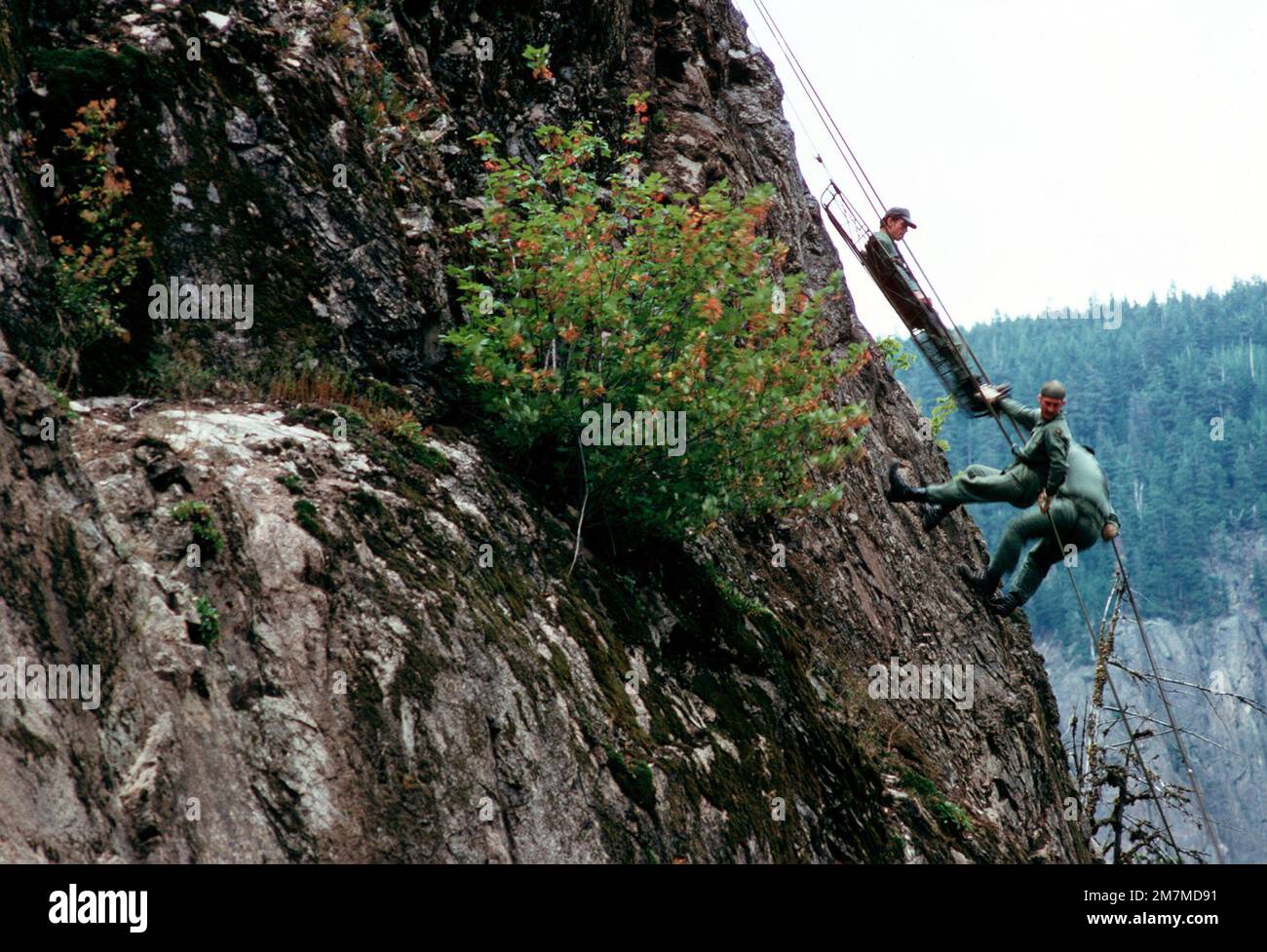 Army personnel rappel down the face of a mountain with a stretcher ...