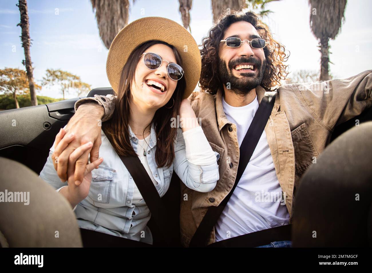 Happy young friends sitting on back convertible car having fun on ...