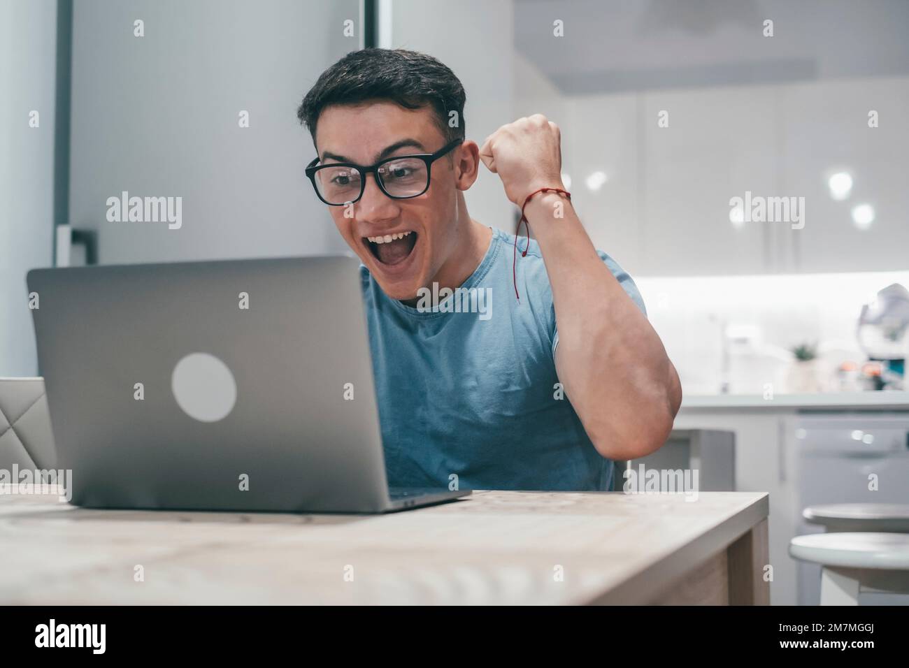 One young man working and winning something with laptop at home. Happy ...