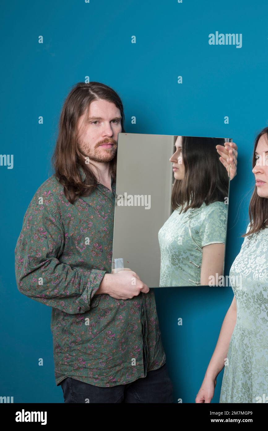 Man holds mirror to woman but she turns away hi-res stock photography ...