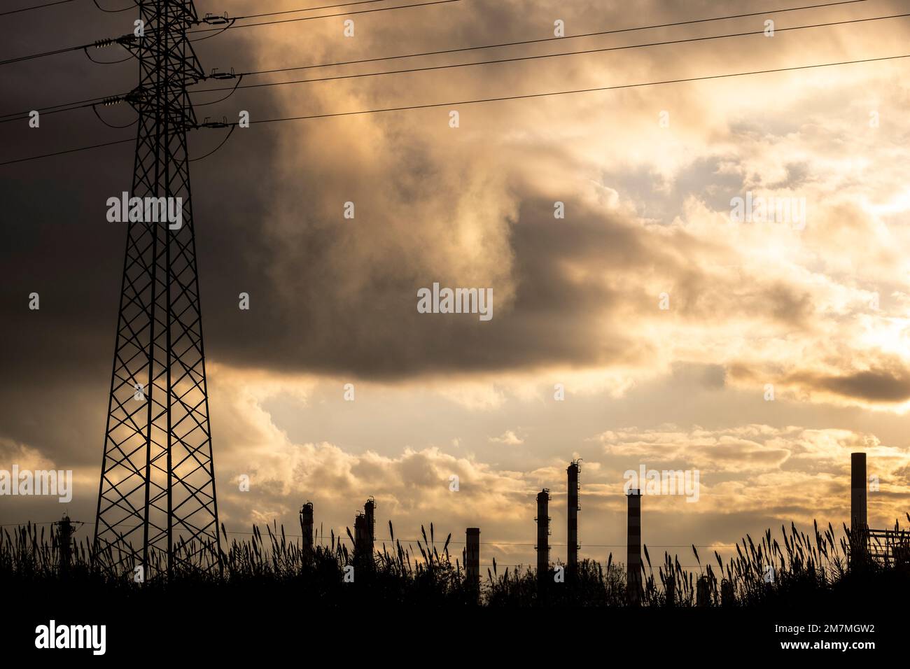 High voltage cable pylons in a dramatic cloudy sunset Stock Photo - Alamy