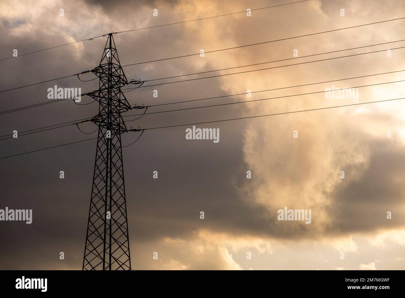 High voltage cable pylons in a dramatic cloudy sunset Stock Photo - Alamy